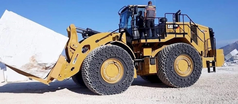 CAT 986K lleva cadenas de protección de neumáticos en una cantera de mármol